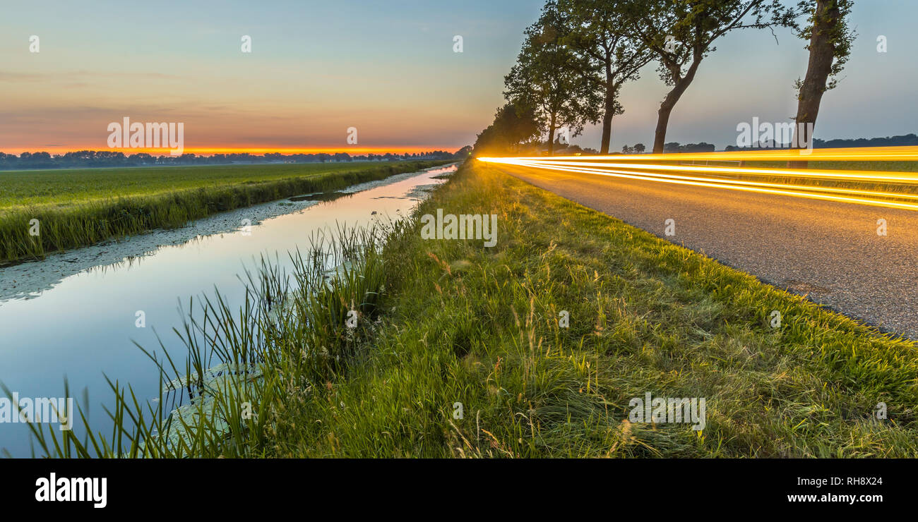 Netherlands open polder landscape with canal and traffic lights on road ...