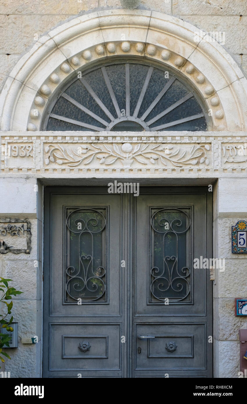 A semi-circular upper window, with a stylized iron grille, stone lintel ...