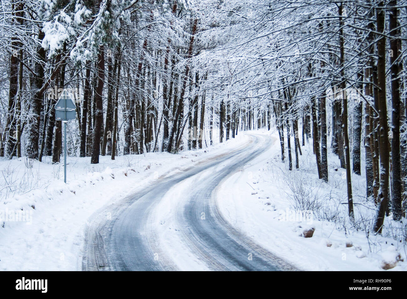 Slippery icy road through the forest with trees and snow on both sides Stock Photo - Alamy