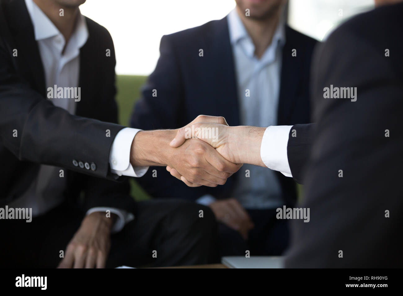 Two businessmen in suits shake hands at meeting, close up Stock Photo ...