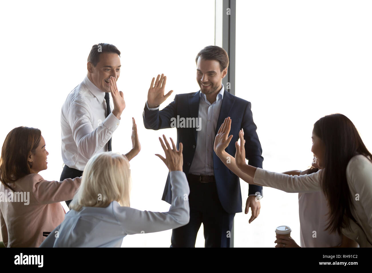 Excited diverse employees giving high five celebrating corporate ...