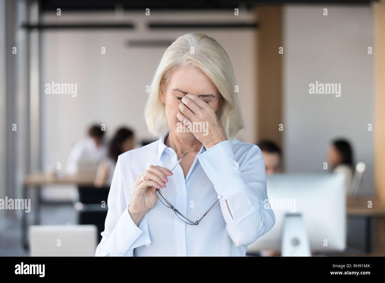 Tired fatigued senior female employee taking off glasses feeling ...