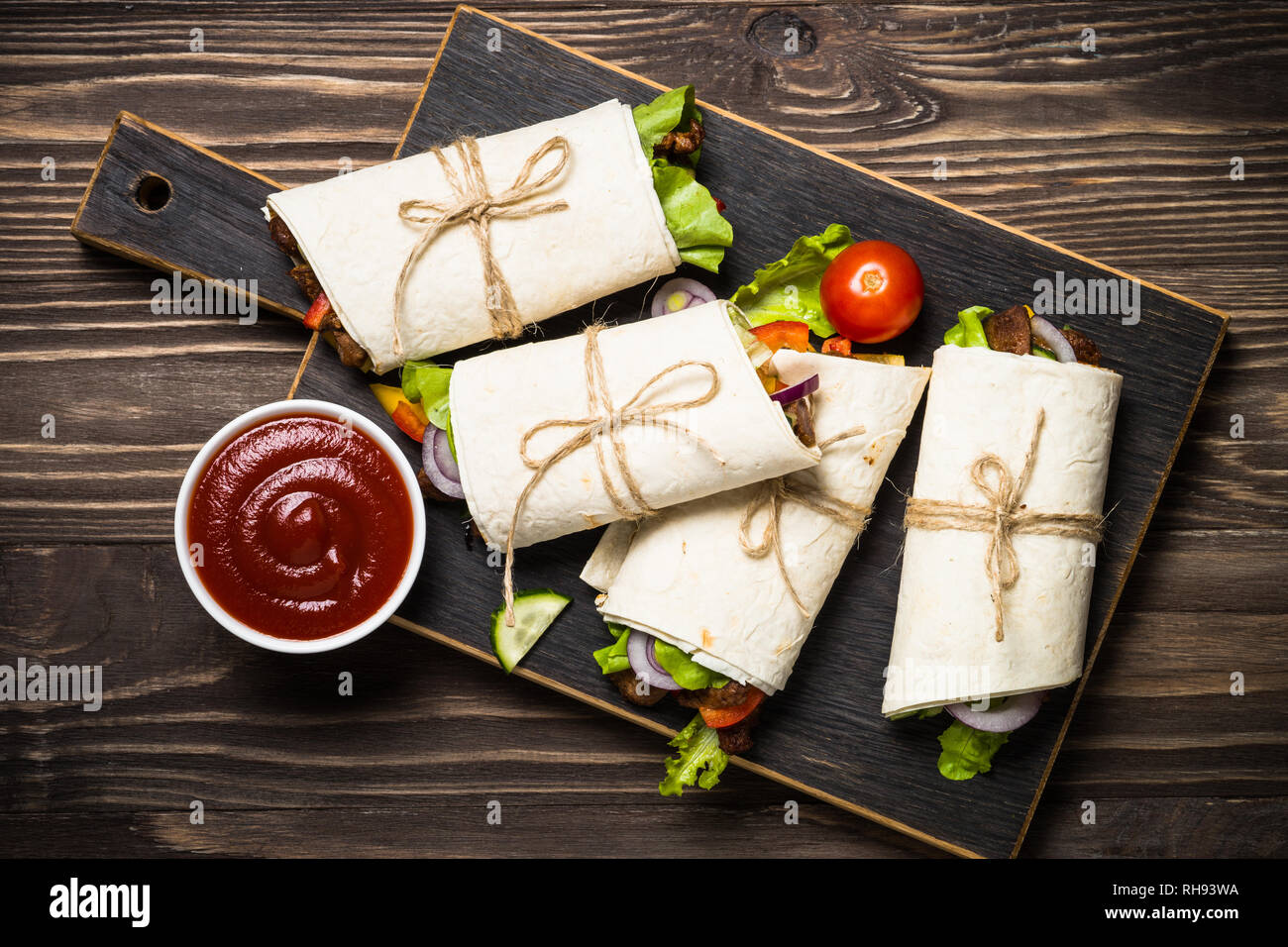 Burritos tortilla wraps with beef and vegetables on wooden table ...