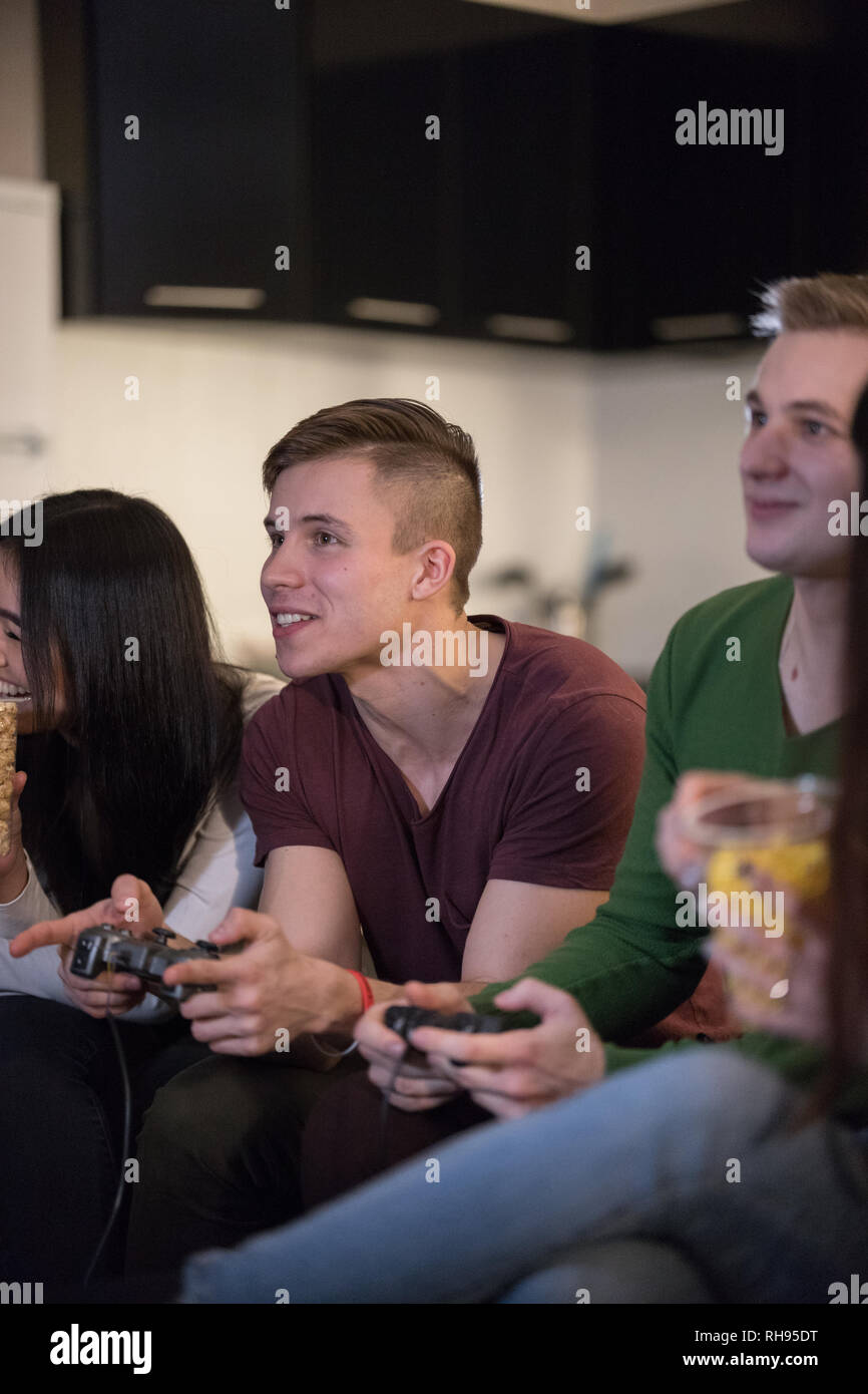 Company of young friends spending time together. Two young men playing ...