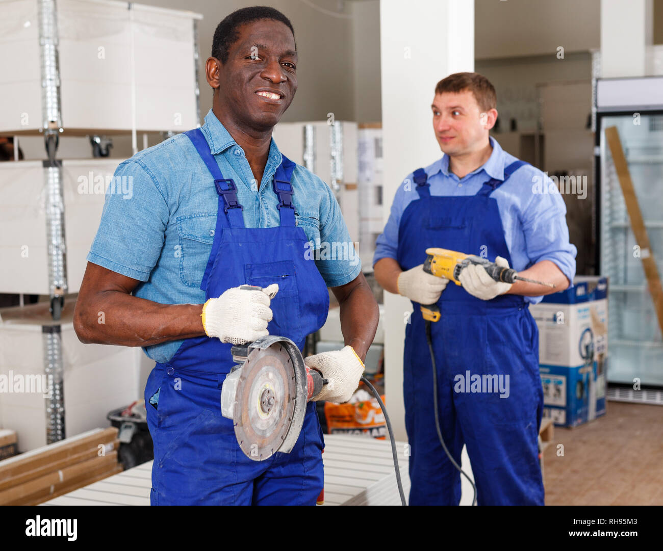 Confident African-American builder holding manual disc grinder, working ...