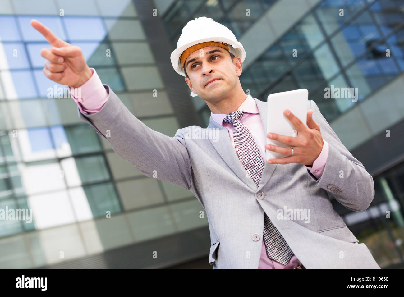 Portrait of manager of plant giving instructions and pointing with his ...