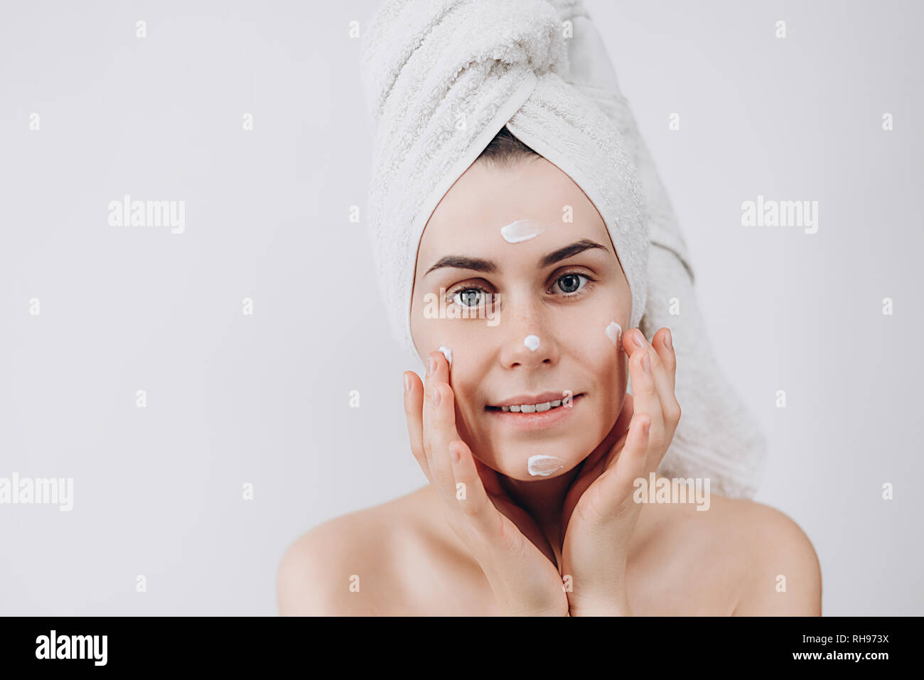 Skin care. A beautiful and smiling woman using a skin care product ...