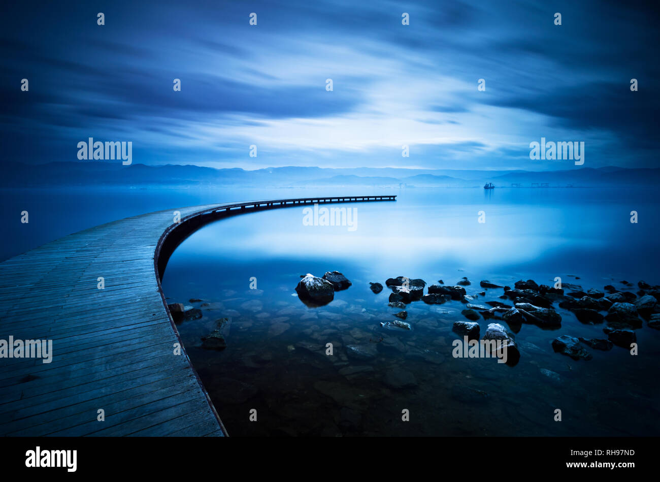 Blue sea and curve jetty , long exposure photography Stock Photo - Alamy