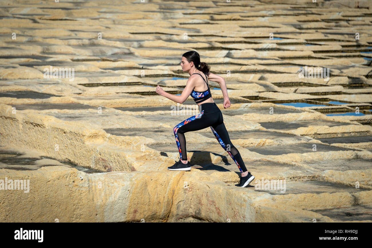woman runner, running across limestone salt pans in Malta Stock Photo ...