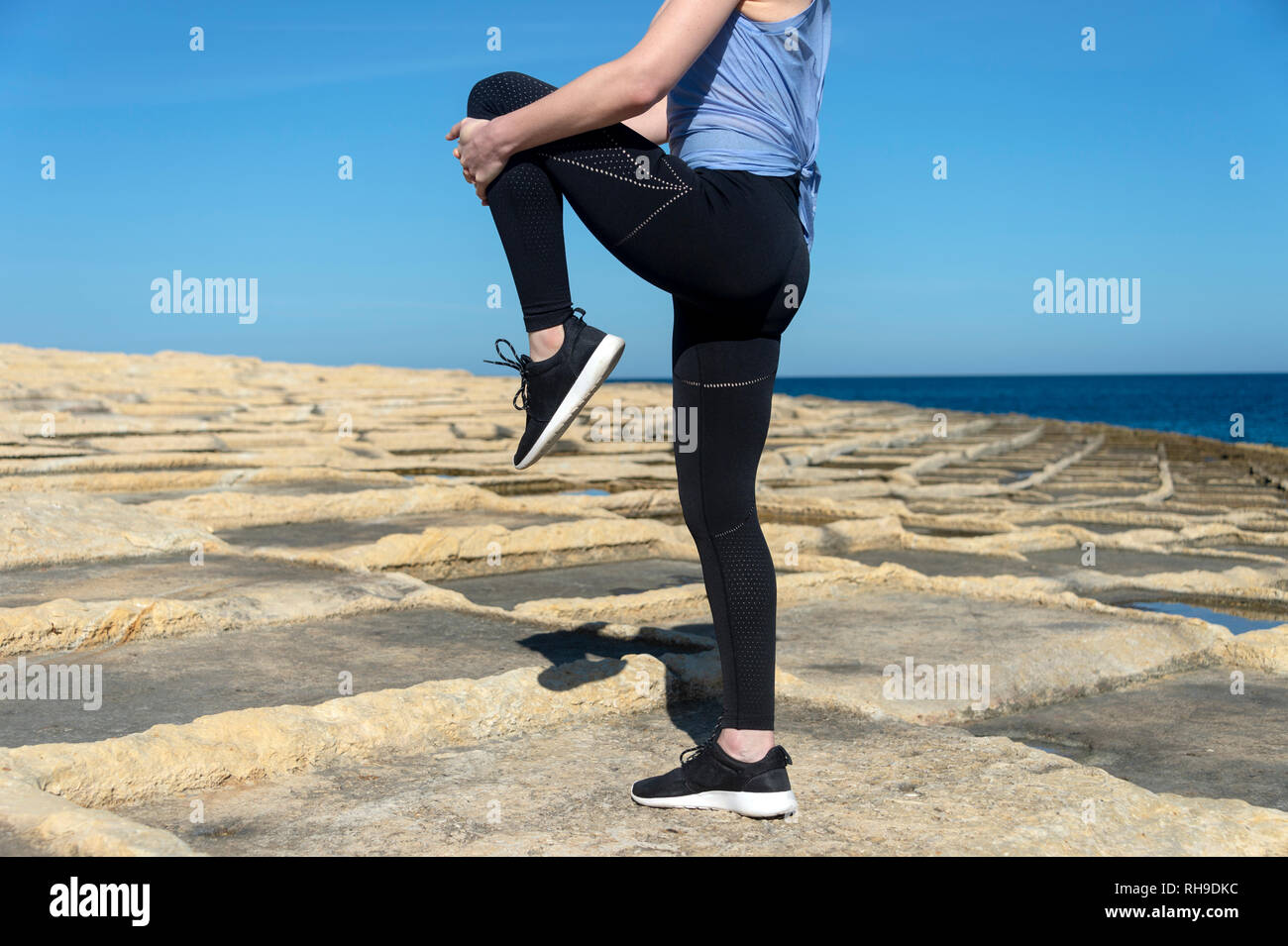 close up of a woman doing a leg stretch warm up exercise, outside in ...