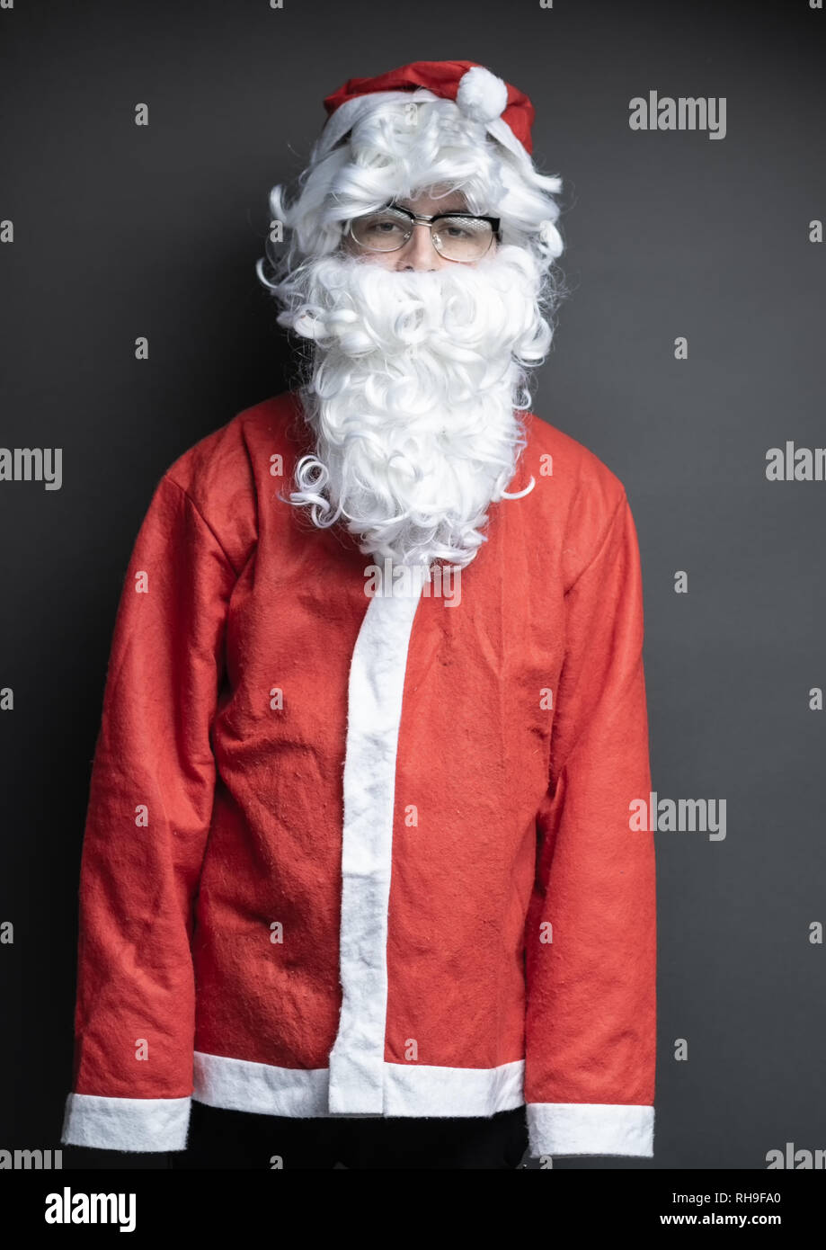 portrait of awkward santa claus with oversized costume in front of grey ...