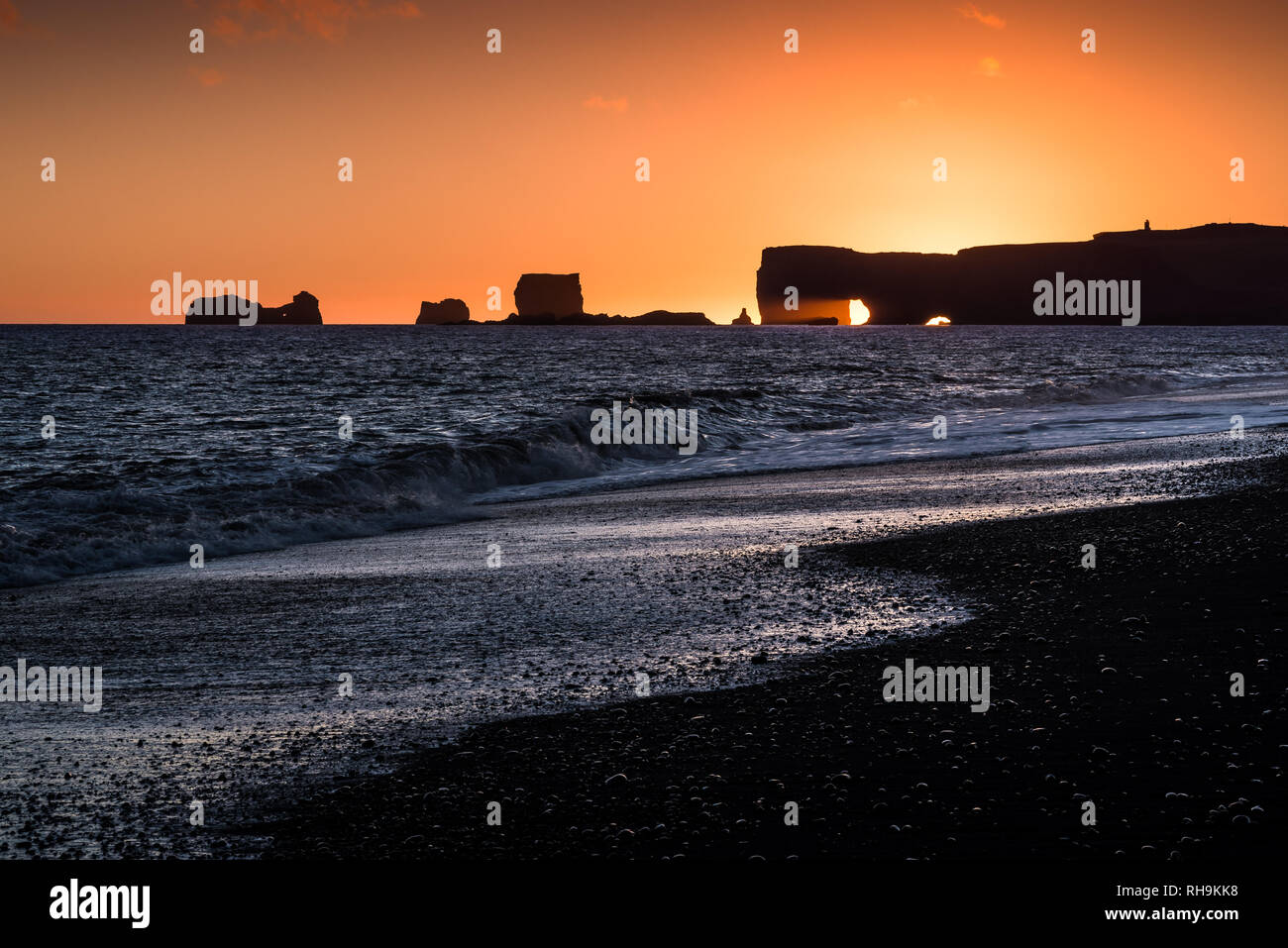 sunset over the coast with the rock arch of Cape Dyrhólaey Stock Photo ...