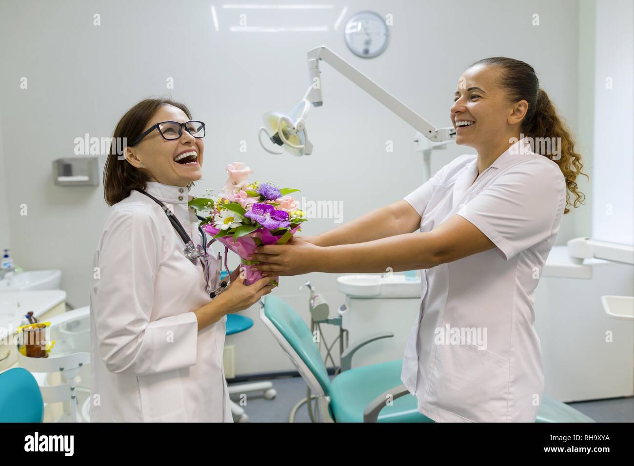 Two female dentists with a bouquet of flowers in the dental office ...