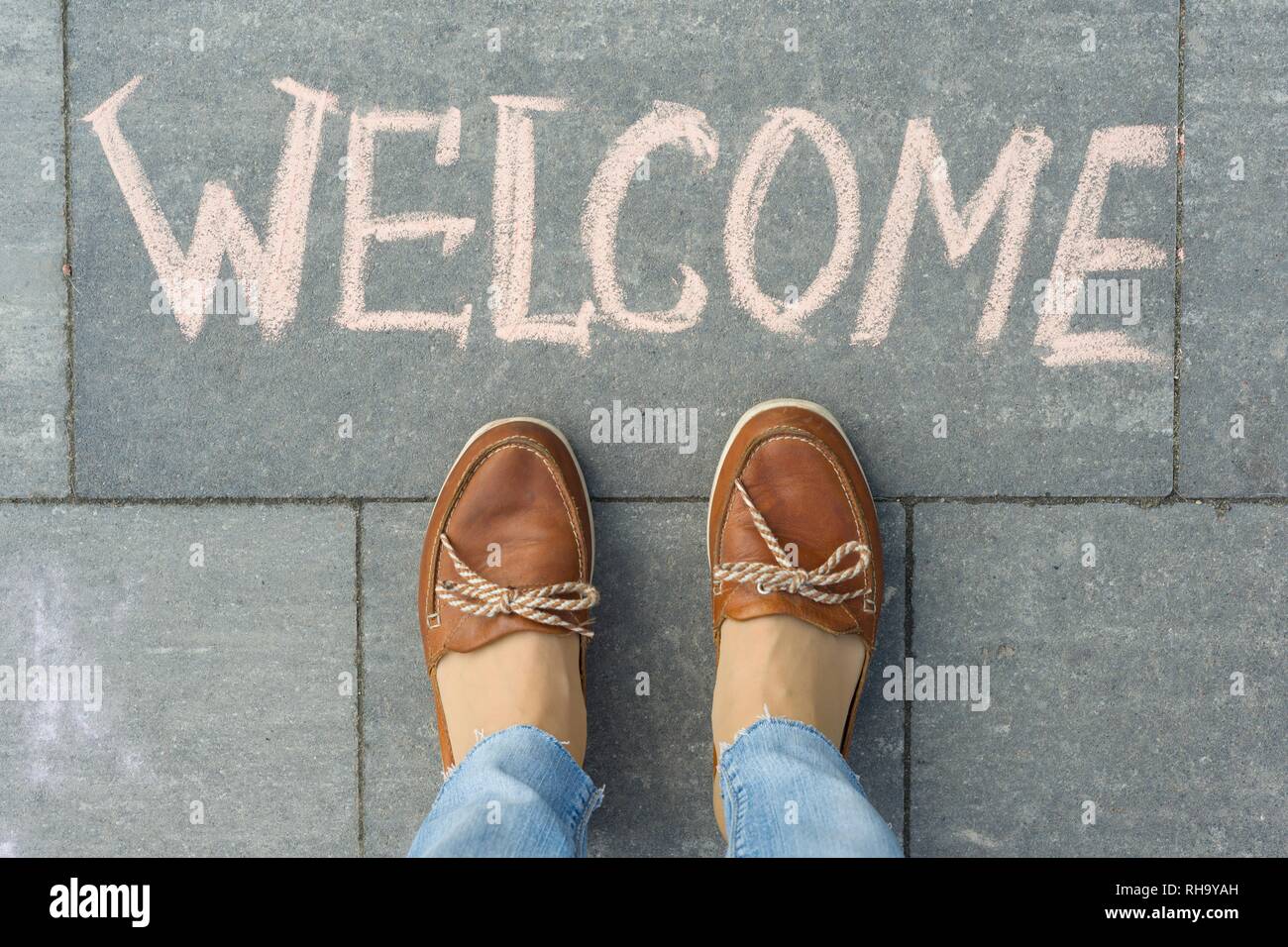 Female feet with text welcome written on grey sidewalk Stock Photo - Alamy