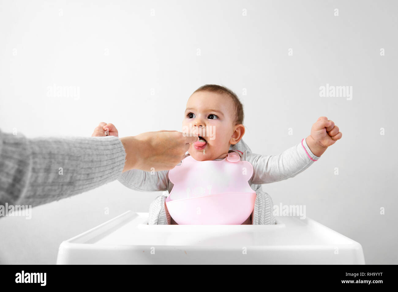 Happy baby toddler in high chair with spoon in his hand Stock Photo - Alamy