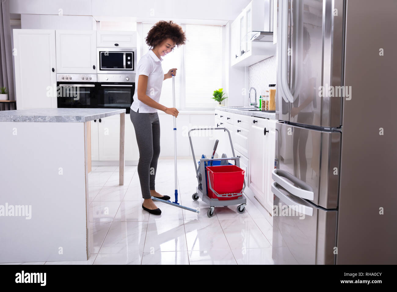 Female Janitor Cleaning The White Floor With Mop In Modern Kitchen ...