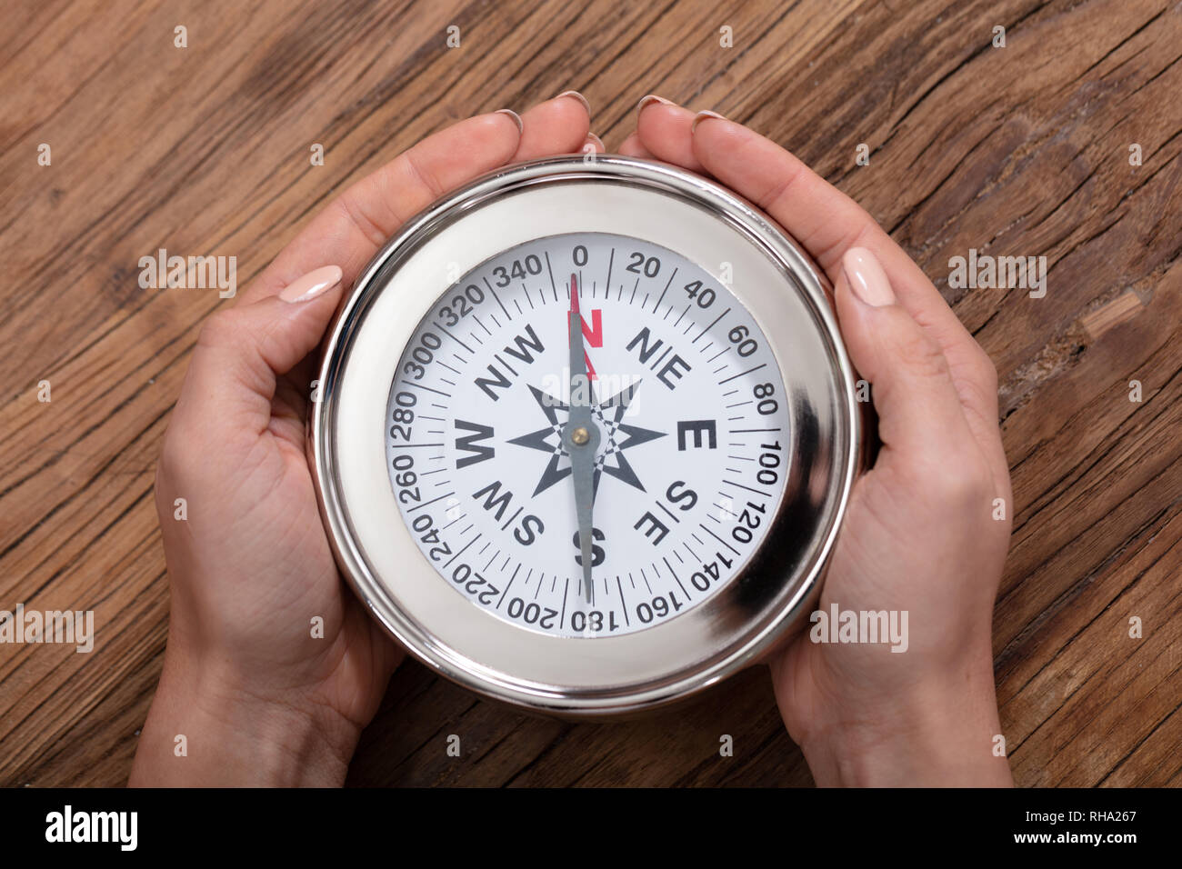 Elevated View Of A Woman's Hand Holding Compass Over Wooden Desk Stock ...