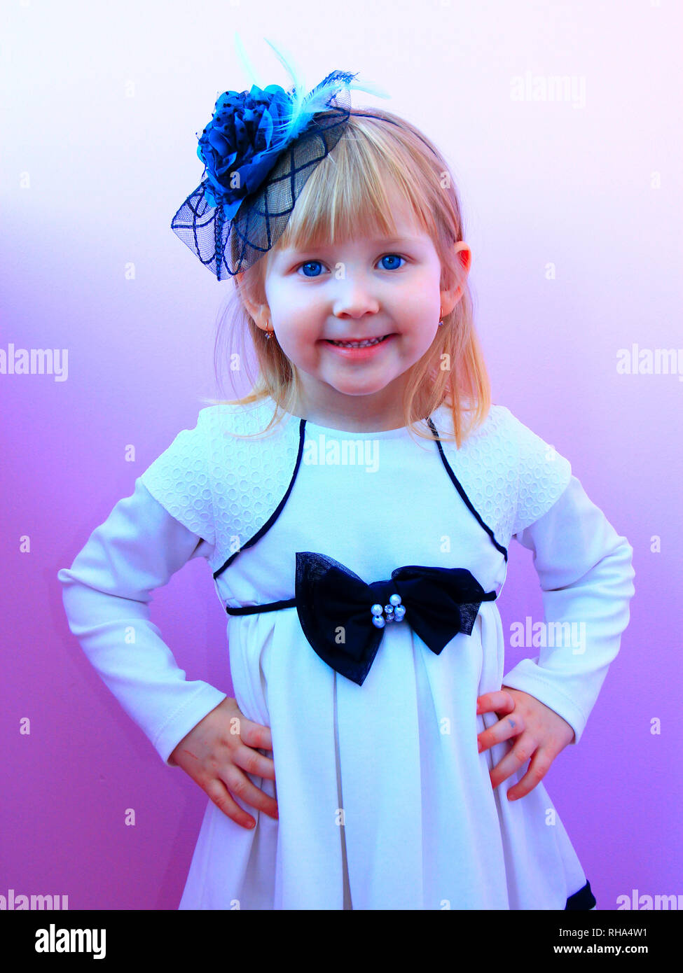 Little girl in fashionable hat smiling and posing on lilac background ...
