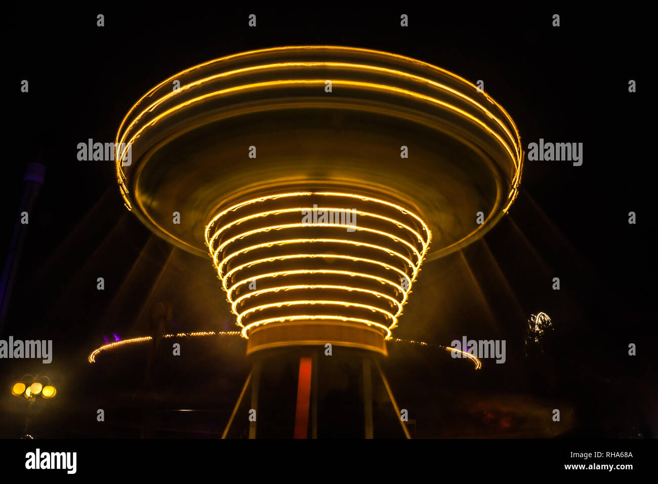 A blurry colorful chain carousel in motion at the amusement park, night illumination. The effect ...
