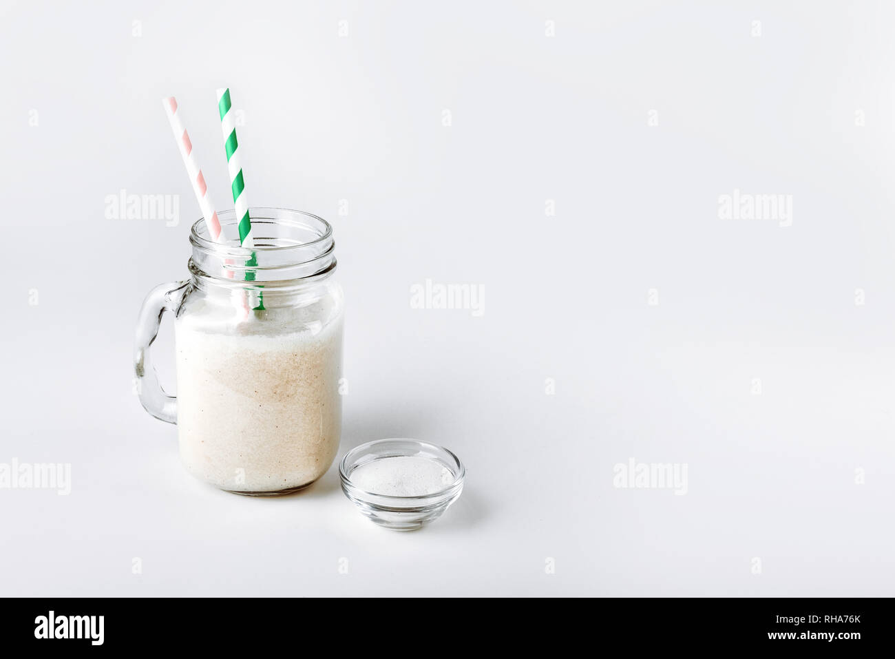 Protein shake on milk in a glass and powder of dry protein on a light ...