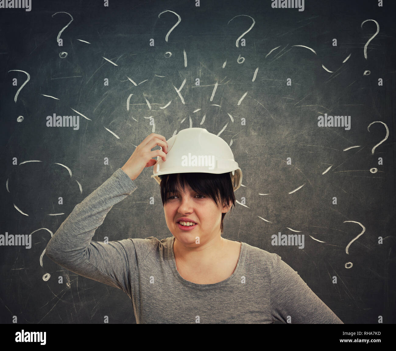 Confused young woman engineer wearing protective helmet pointing to ...