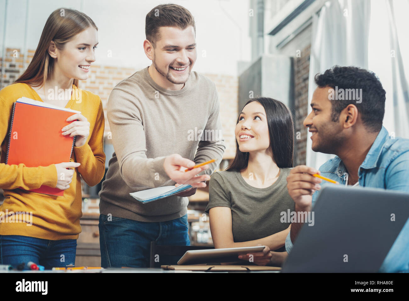 Attractive four students brainstorming Stock Photo - Alamy