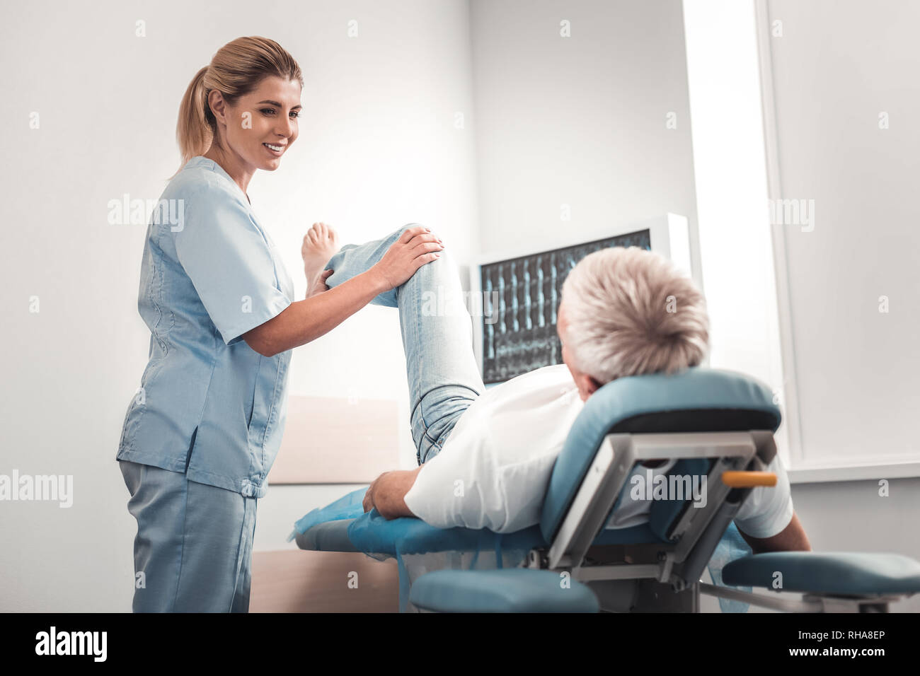 Beautiful doctor doing leg exercises for man Stock Photo - Alamy