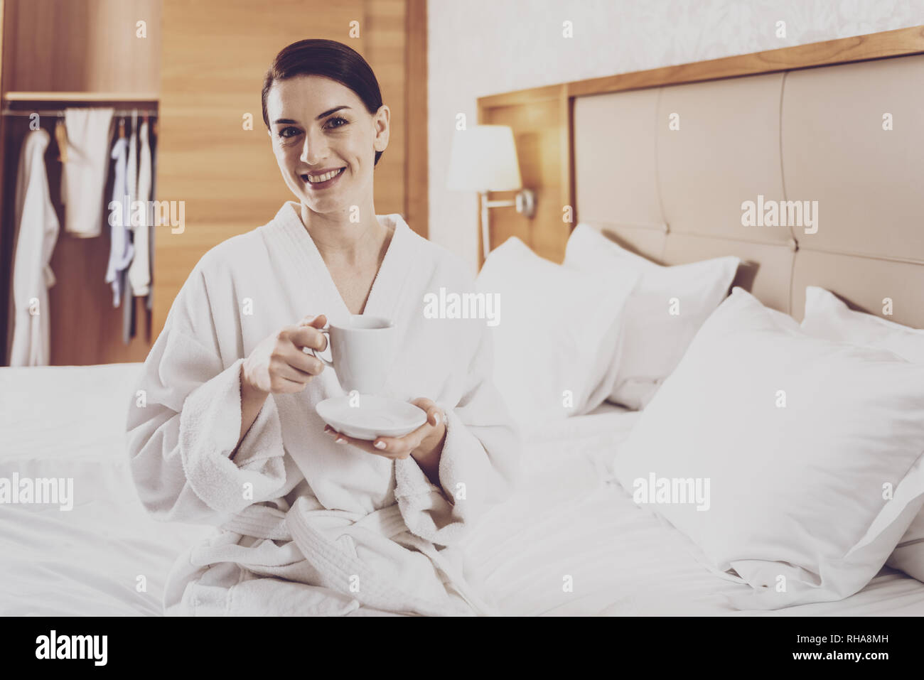 Presentable woman sitting on bed in hotel Stock Photo - Alamy