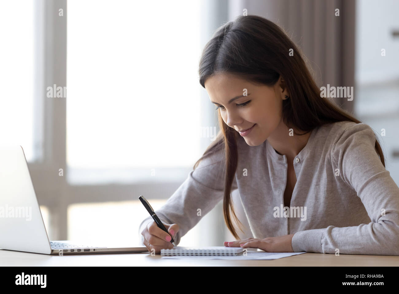 Young woman writing notes in notebook making list planning tasks Stock ...