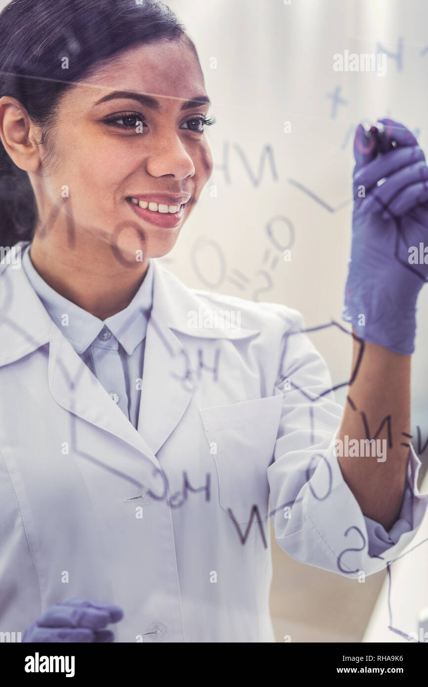 Young chemist wearing glove writing molecular chain Stock Photo - Alamy