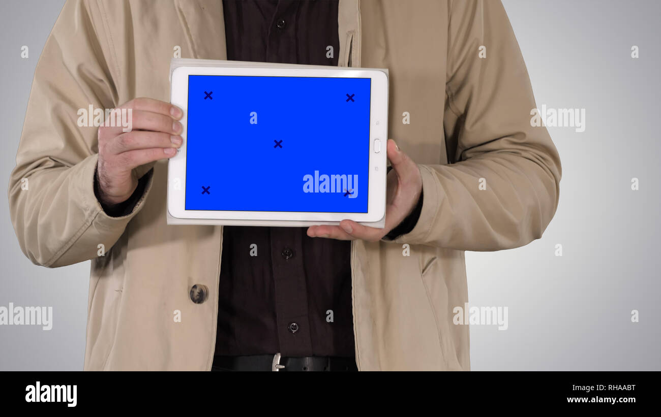 Male hands holding tablet with blue screen mockup on gradient ...