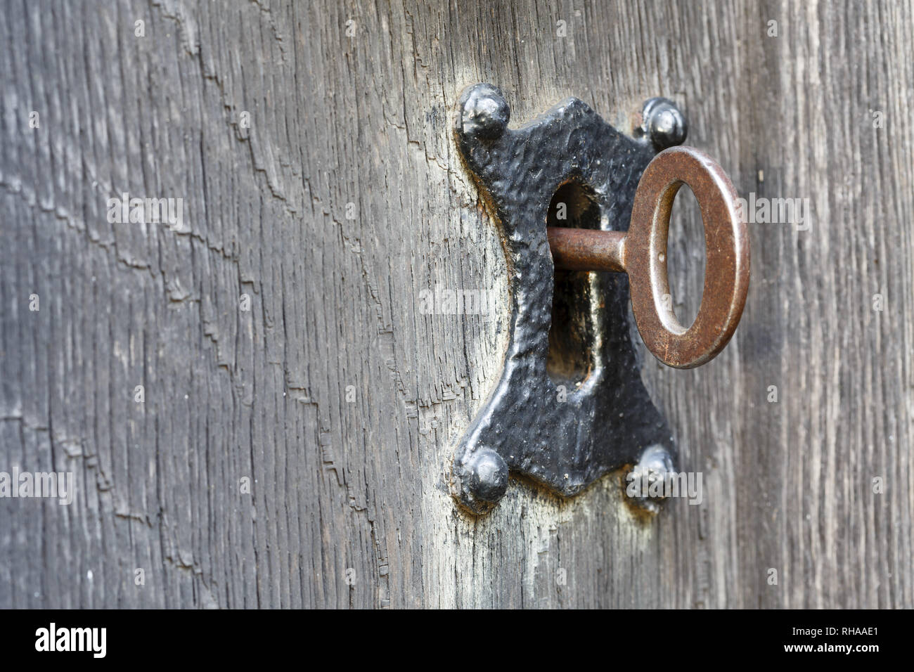Closeup of an old key in a traditional keyhole lock and ancient wooden ...