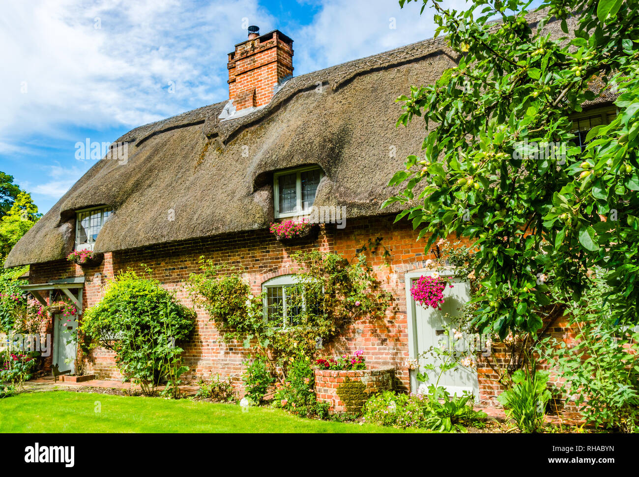 A traditional English country house with thatch roof. Brick house with ...