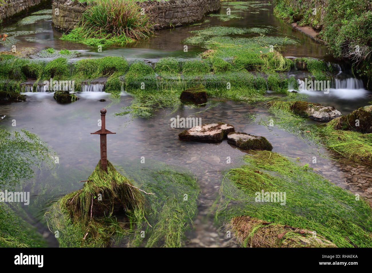 Long exposure of the river flowing past a sword sticking out of the ...