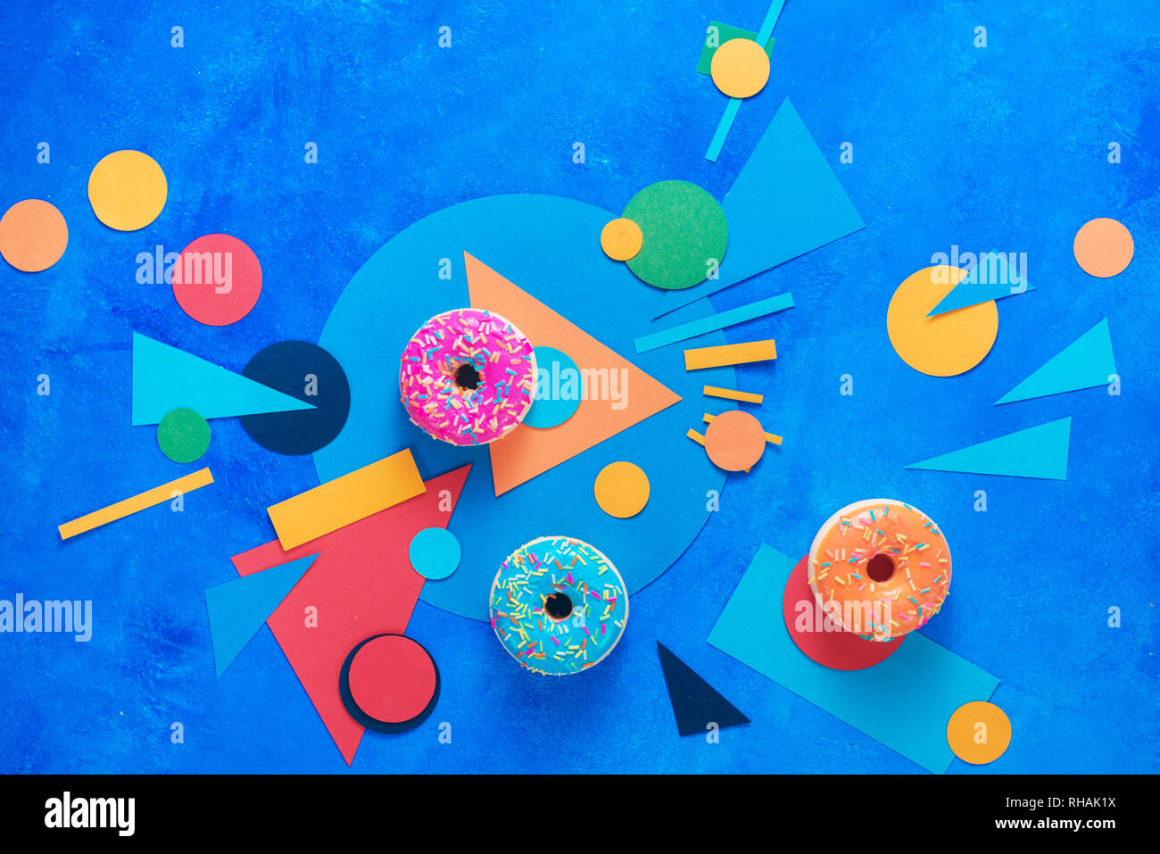 Donuts with colorful paper decorations. Color blocking flat lay header ...
