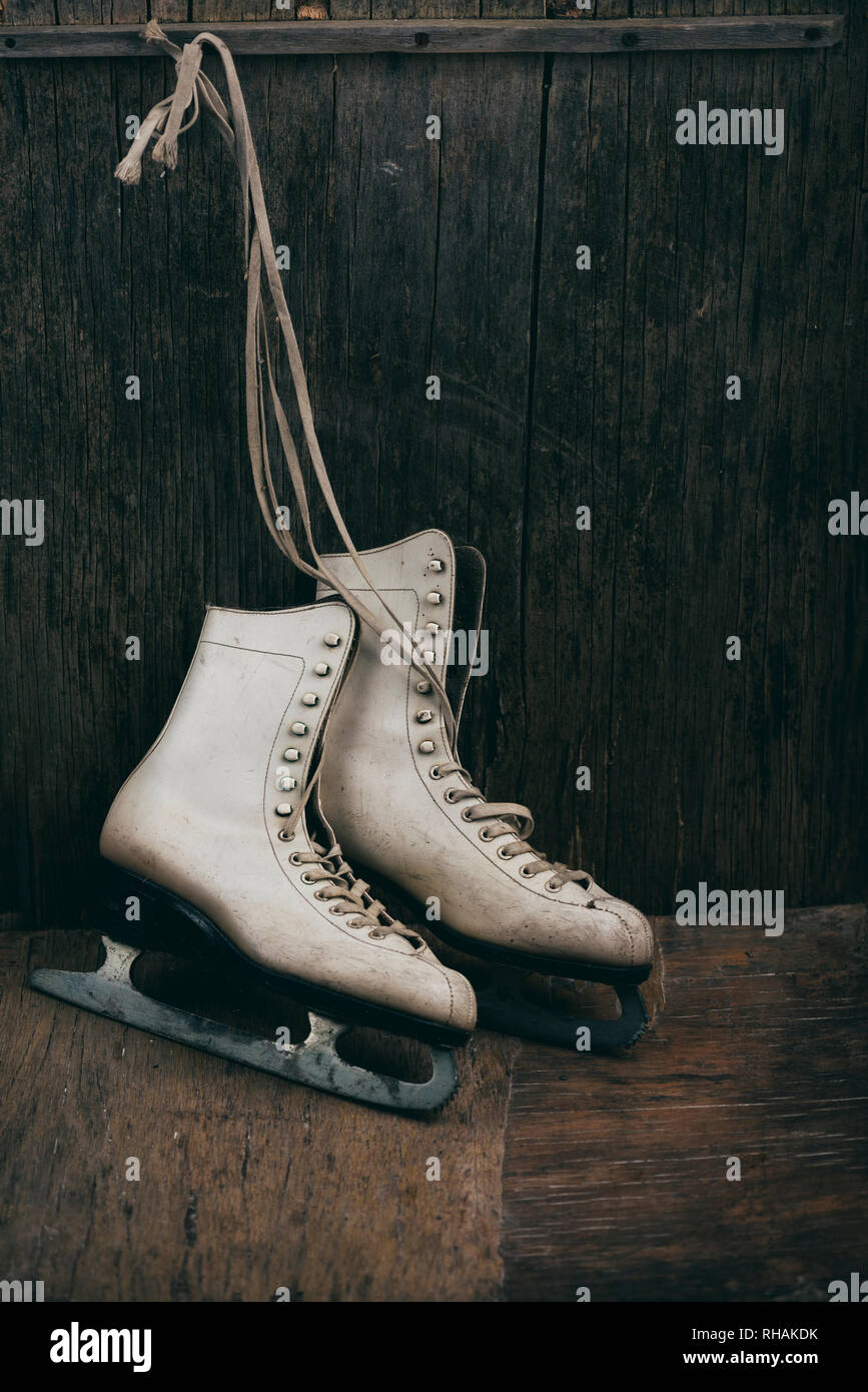 Seasonal winter holiday scene with pair of white ice skates on rustic ...