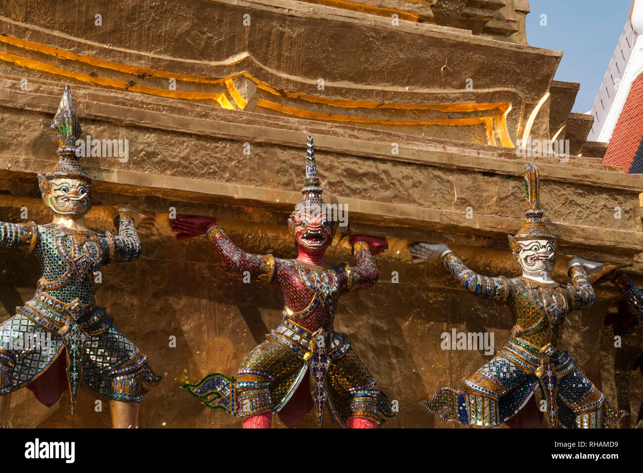 Bangkok Thailand, row of mirrored demons with masks holding up golden ...