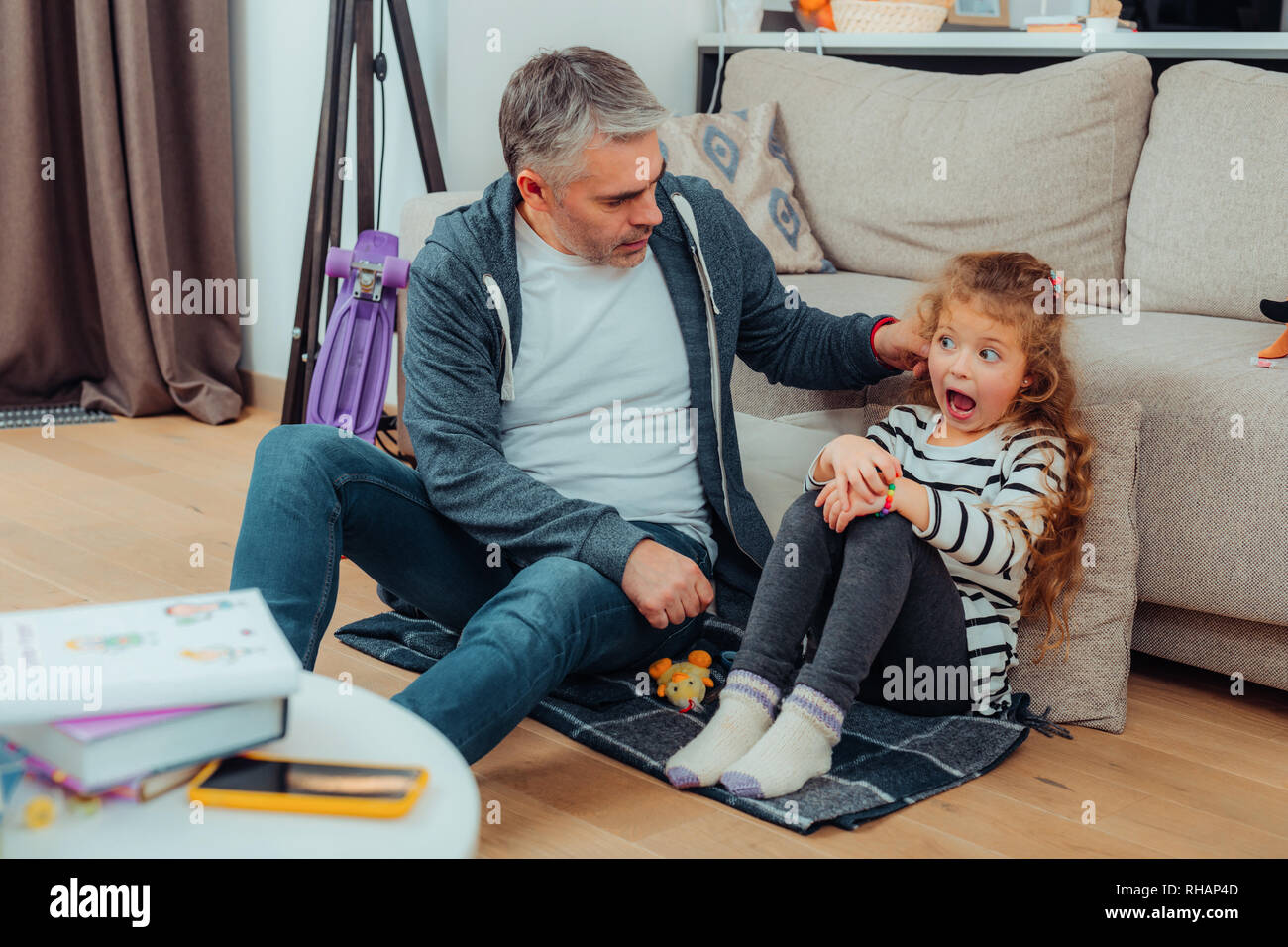 Handsome grey-haired tall father with a red watch pulling his daughters ...