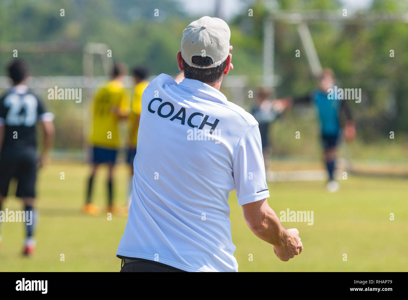 Back view of male football coach in white COACH shirt at an outdoor ...