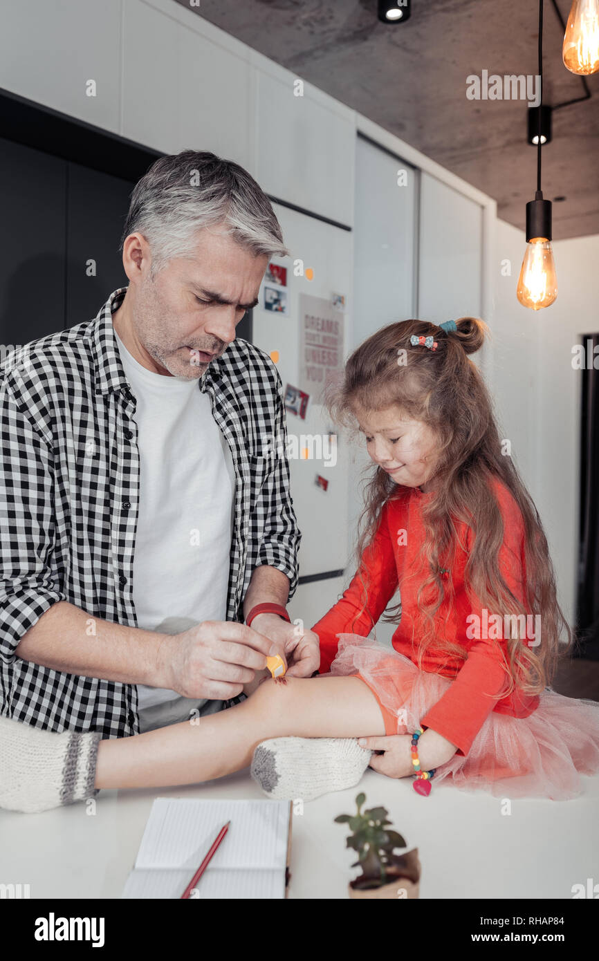 Tall grey-haired father with a red watch on his hand curing his ...