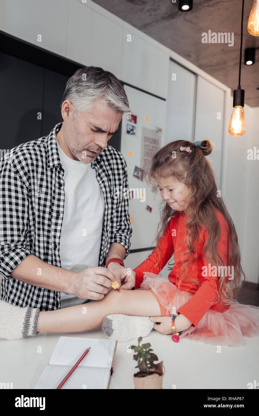 Tall grey-haired father with a red watch on his hand helping his ...
