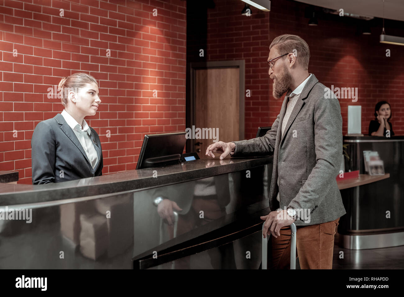 Pleased young manager talking to her visitor Stock Photo - Alamy