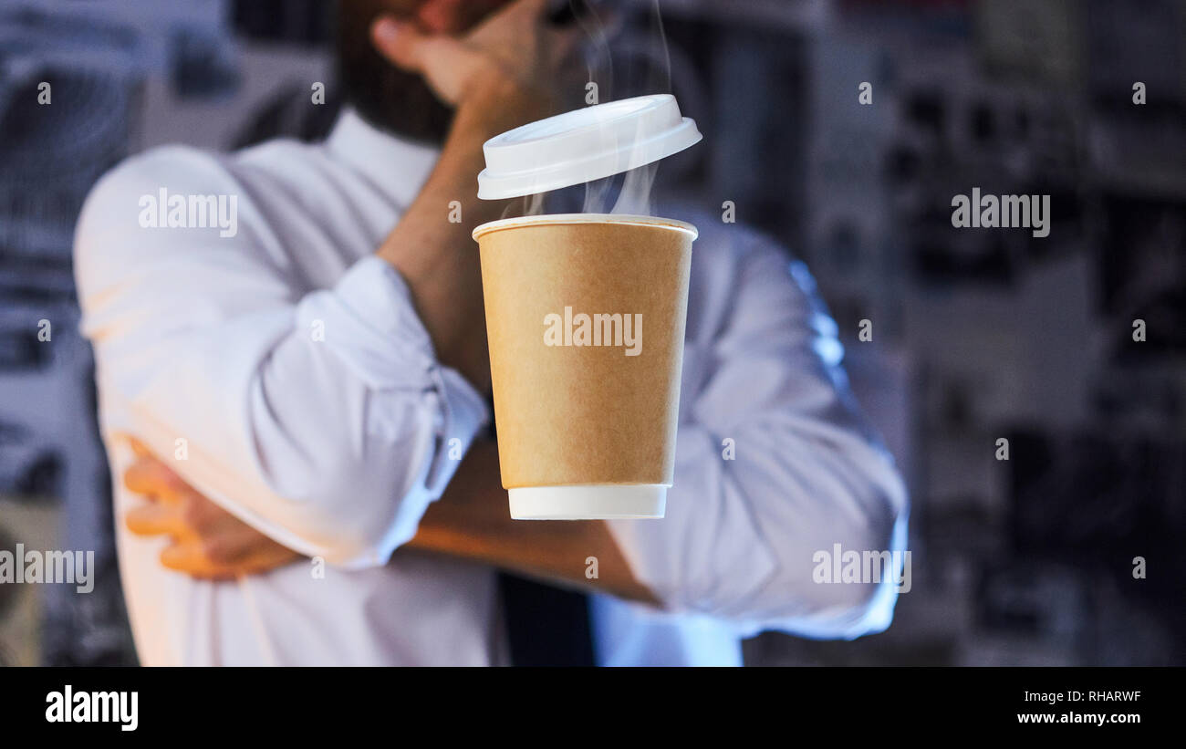 Meditative barista in a white shirt and tie and levitating paper cup of ...
