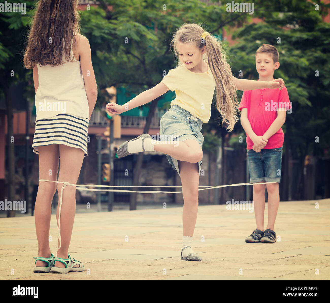 Happy kids in school age playing together with chinese jumping rope ...
