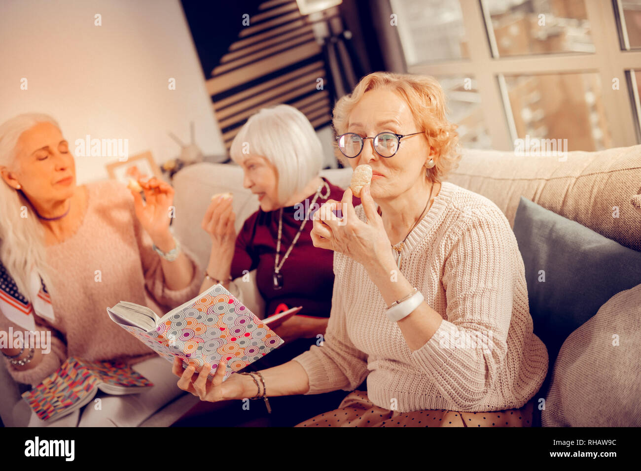 Nice positive aged woman smelling a cookie Stock Photo - Alamy