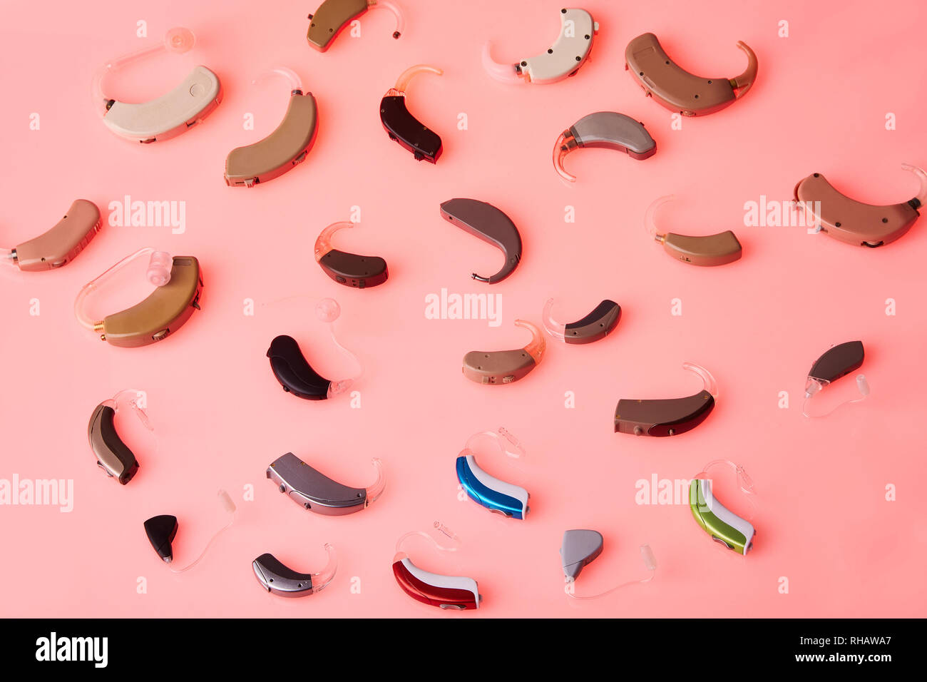 Different hearing aids on pink background, alternative to surgery. ENT ...