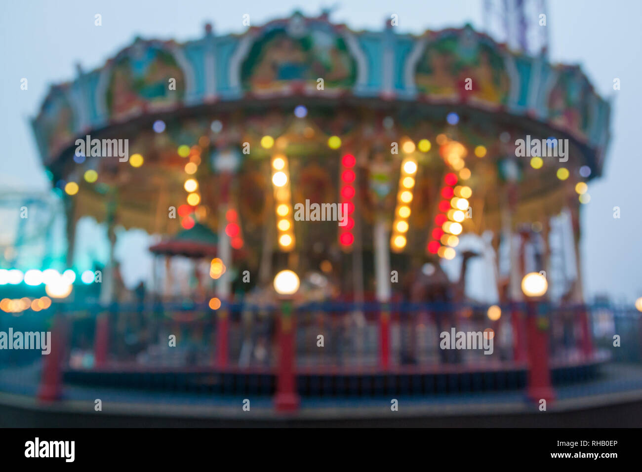A blurry colorful carousel in the amusement park at evening illumination. The effect of bokeh ...