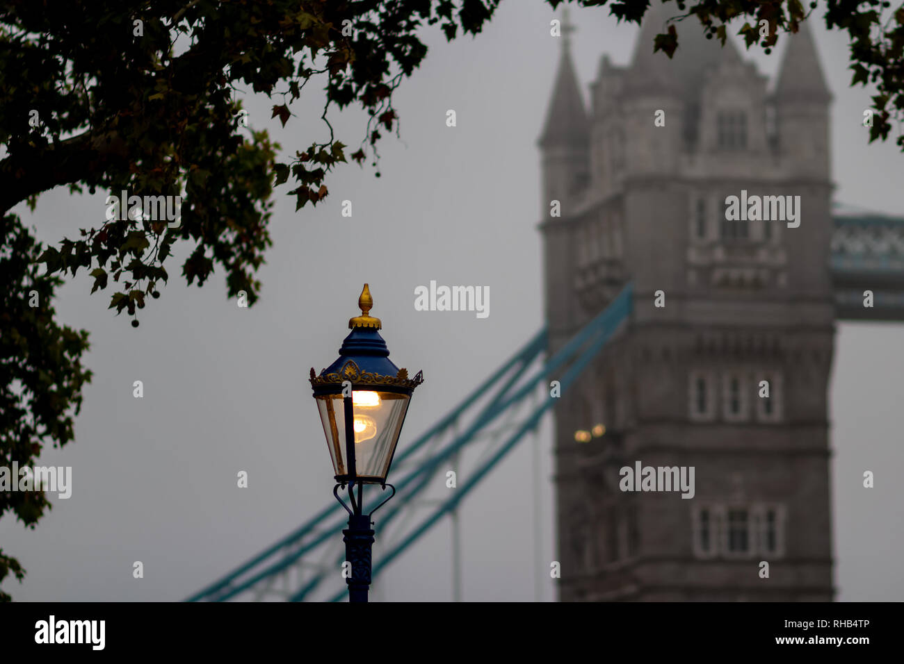 Street lantern against the Tower bridge in deep morning fog. London ...