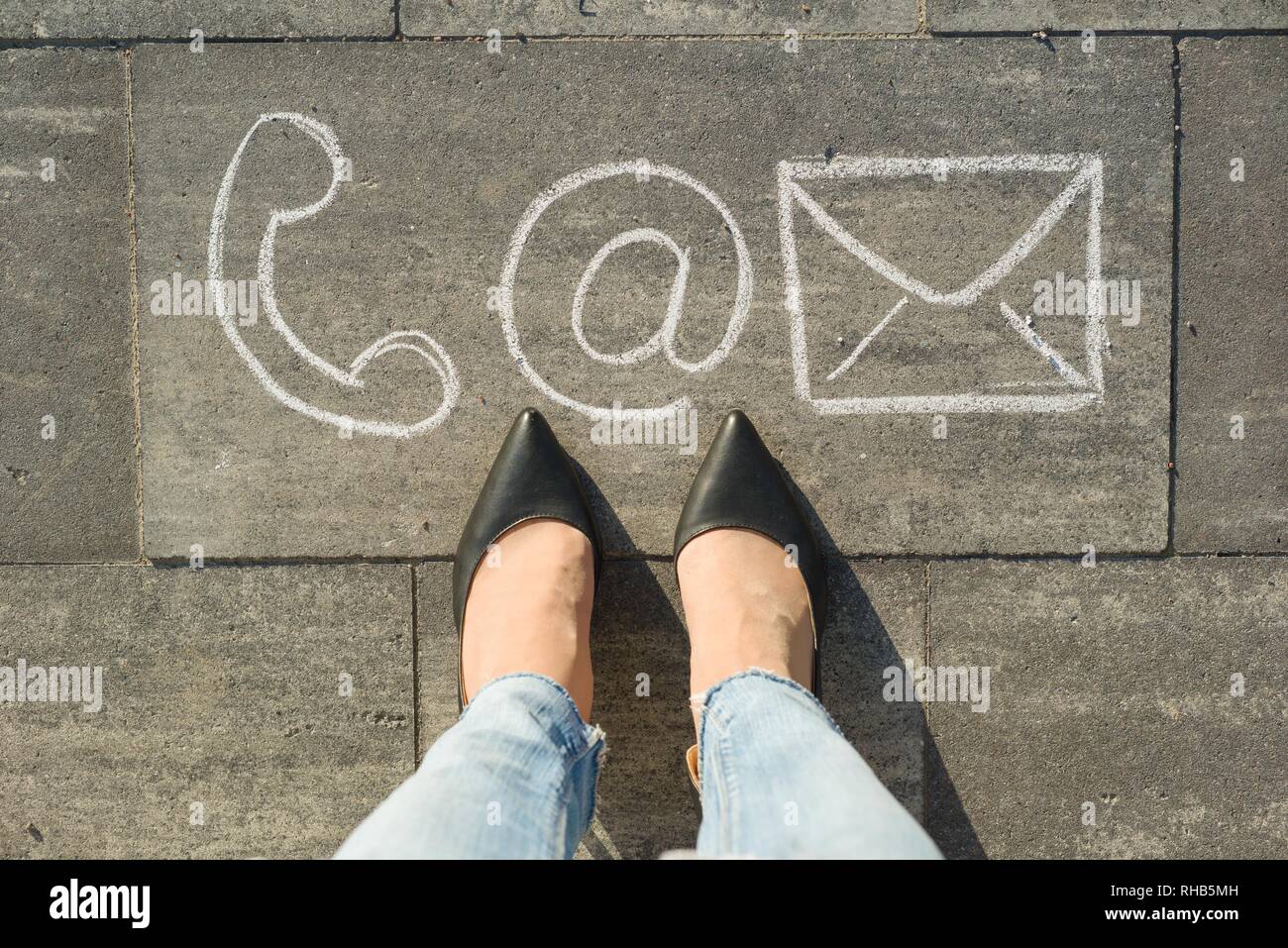 Female feet with contact symbols phone mail and letter, written on grey ...