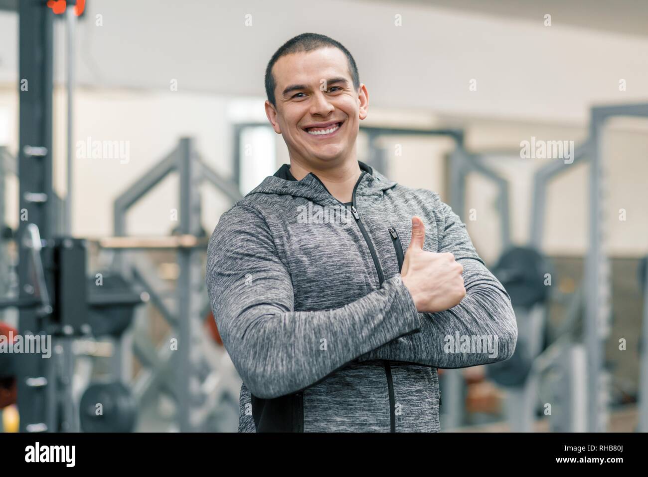 Portrait of muscular sporty smiling man showing thumbs up in gym ...